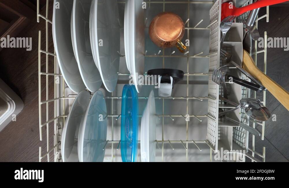 Man loading dirty kitchen dishes into dishwasher and closing the door ...