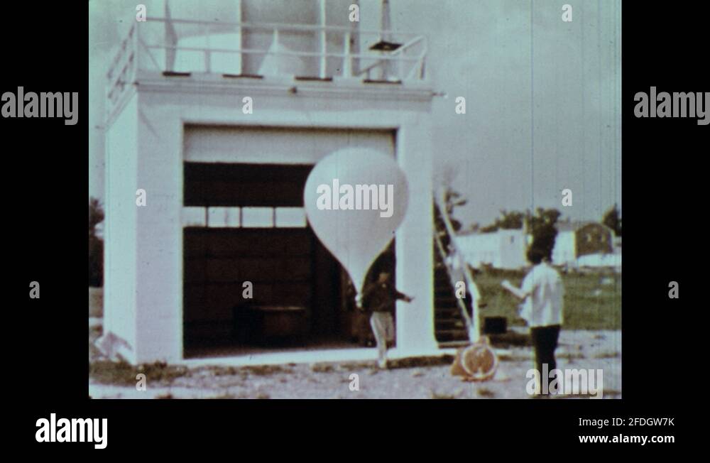 1960s: Two people carry large testing balloon out of building and ...