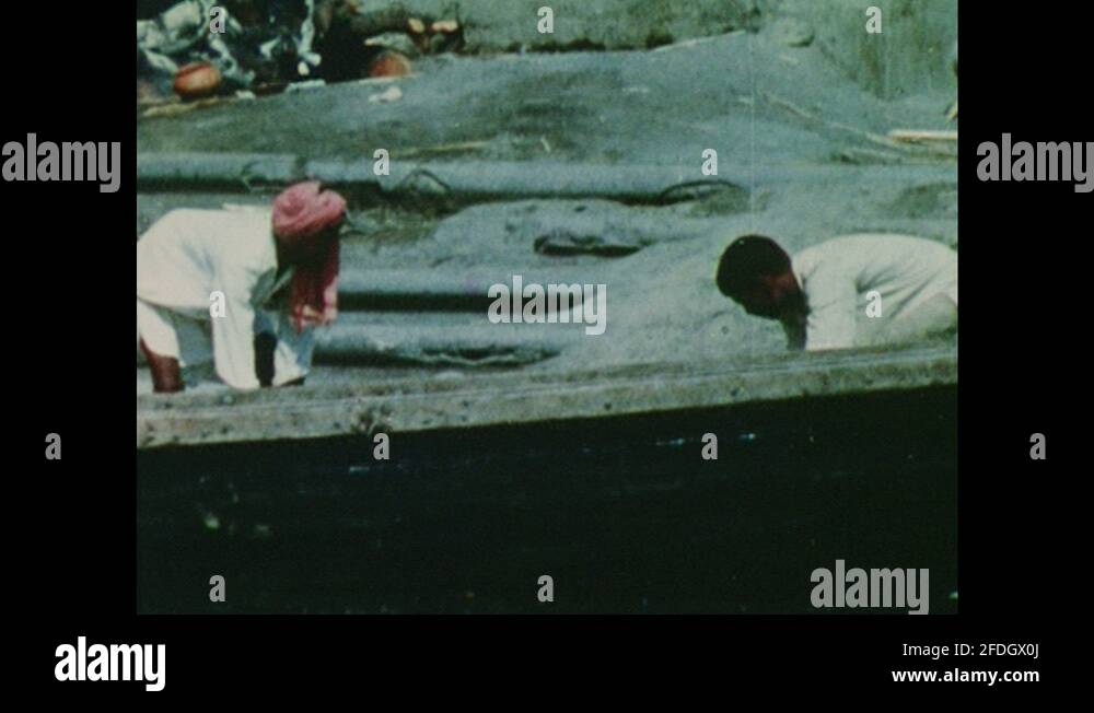 1960s: People carry wrapped corpses on stretchers. Men lay corpse down ...