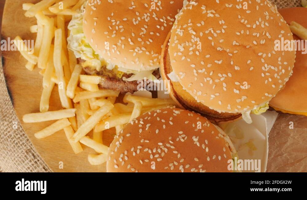 portion of unhealthy food, fast food, stack of burgers, fries rotating ...