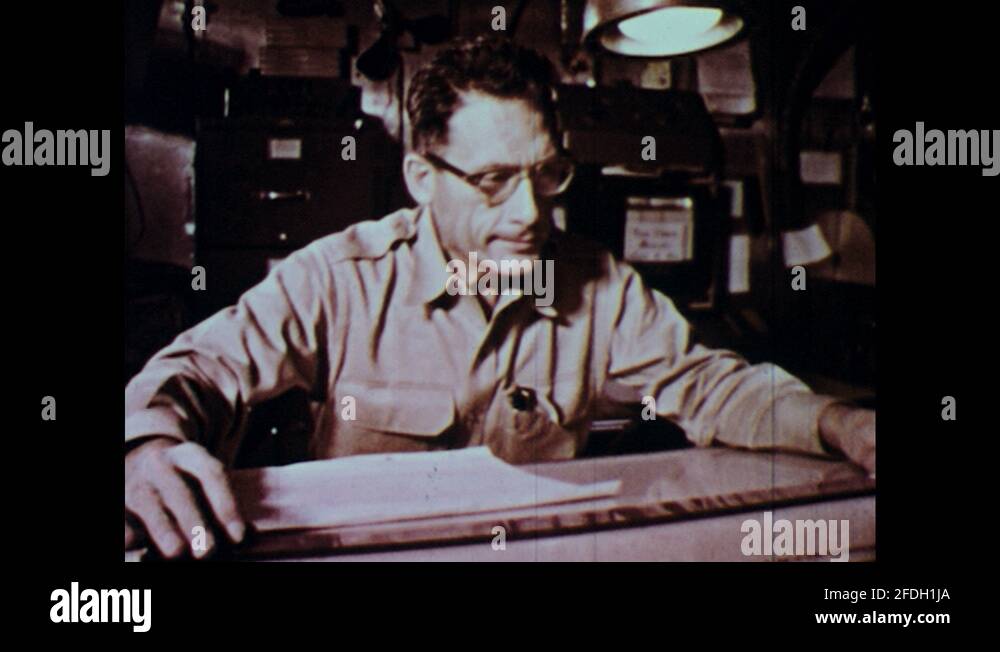 1960s: Man sits at drafting table drawing on map. Man looks over maps ...