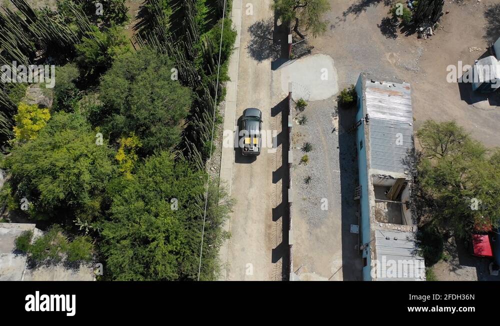 from above a pickup truck drives on dirt road through poor village in ...