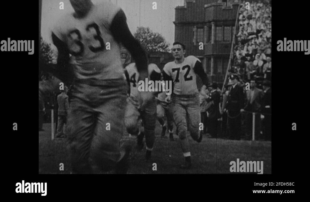 1940s: stadium full of cheering fans, football team running out onto ...