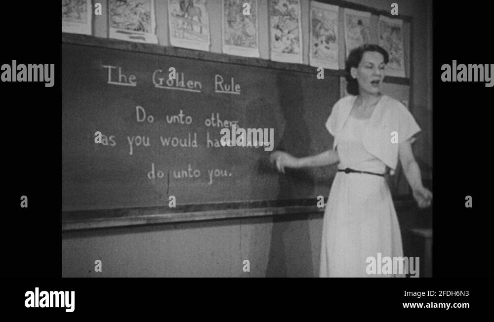 1950s: Teacher speaks and gestures. Students stand up and form a circle ...