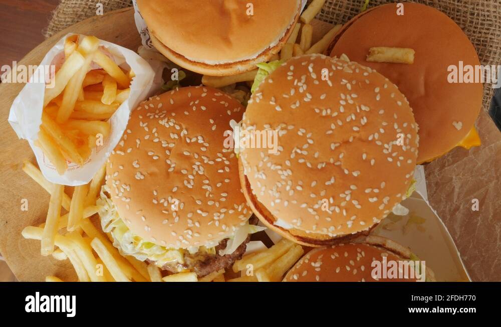 portion of unhealthy food, fast food, stack of burgers, fries rotating ...