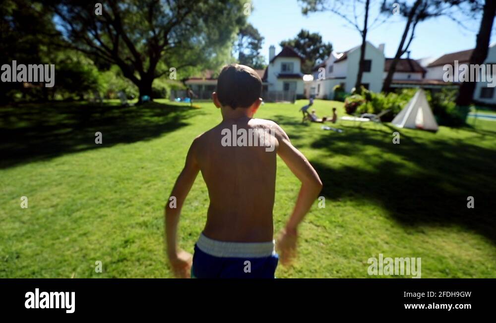 Child boy running in home backyard garden and jumping into swimming ...