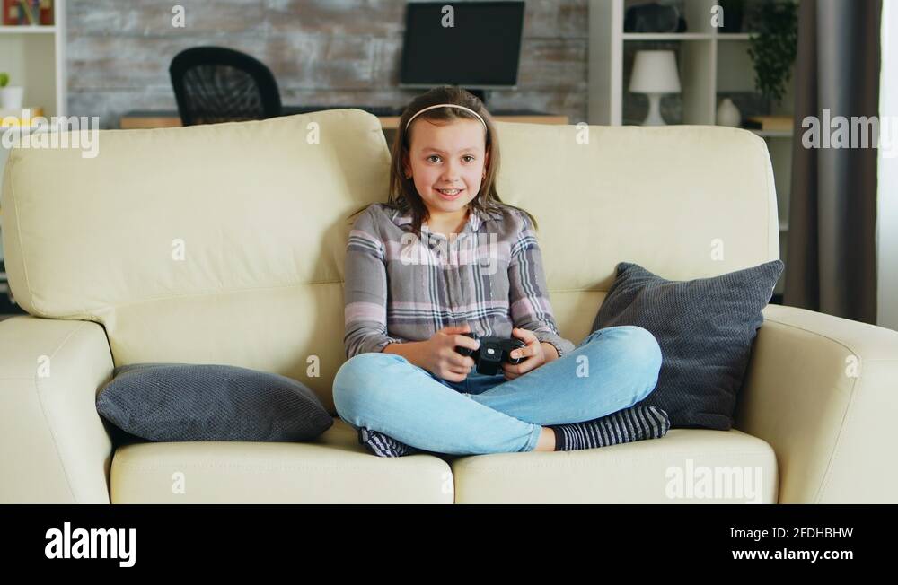 Cheerful little girl playing video games using wireless controller ...
