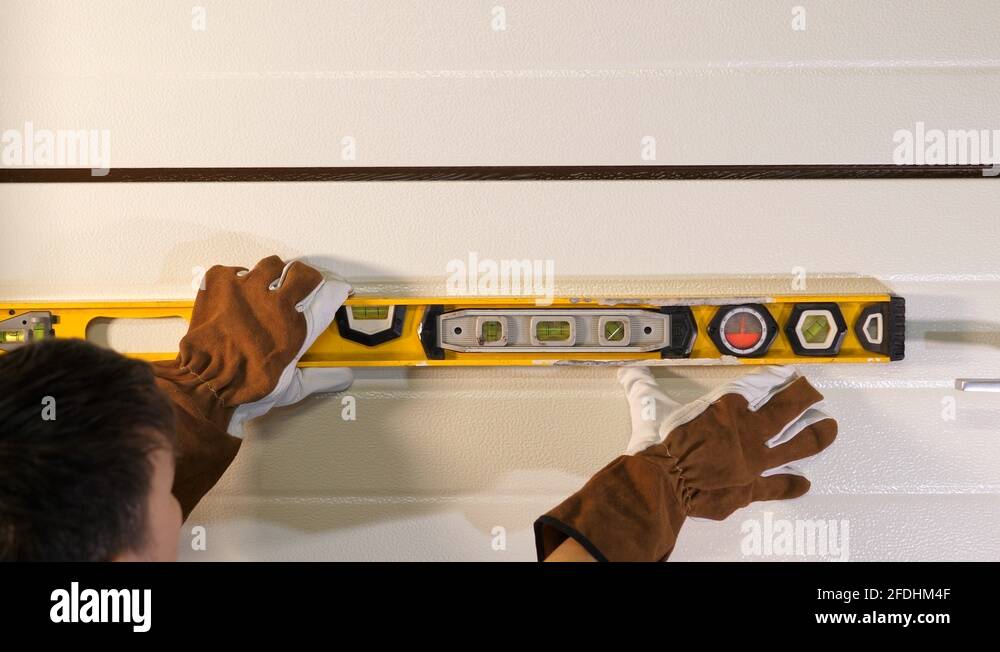 Worker using Level tool device in the garage on wall. Tool consists of ...