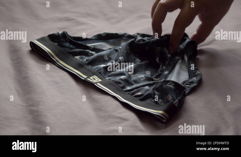 Men use their hands to fold men's underwear to keep it organized and ...