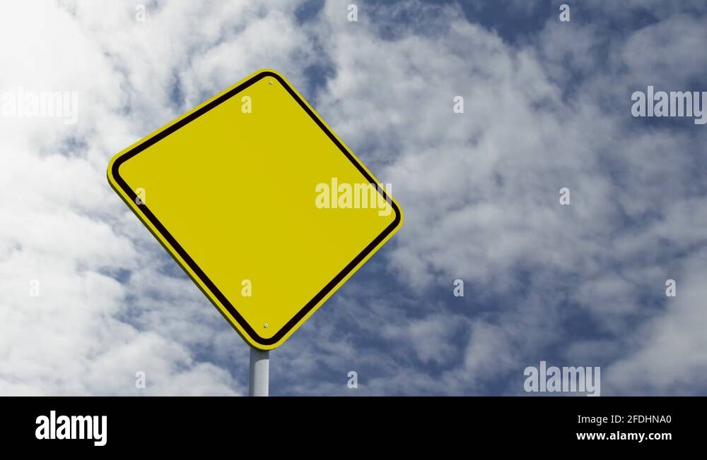 Blank yellow road sign board with clouds moving fast in background ...