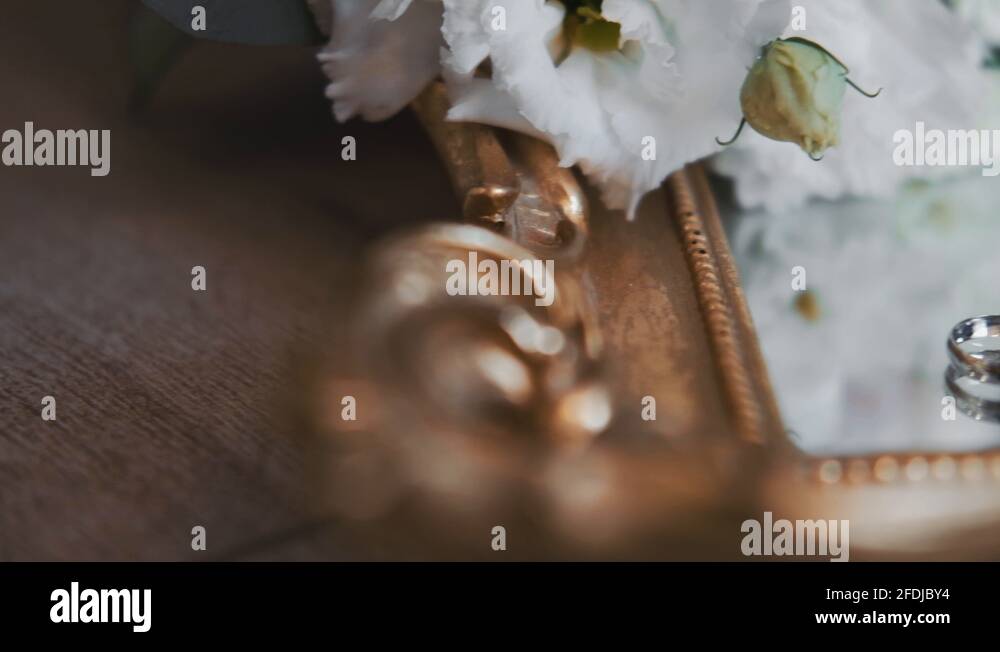 Two golden wedding rings lying on a mirror with a transfusion of light ...
