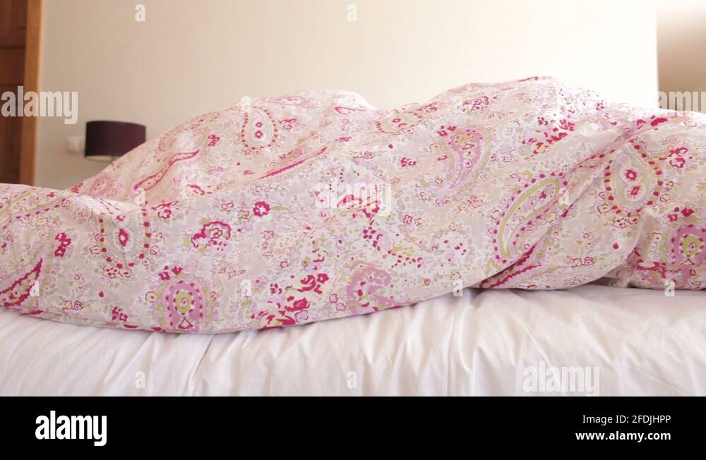 Two girls hiding under sheet in bed before emerging and pulling funny ...