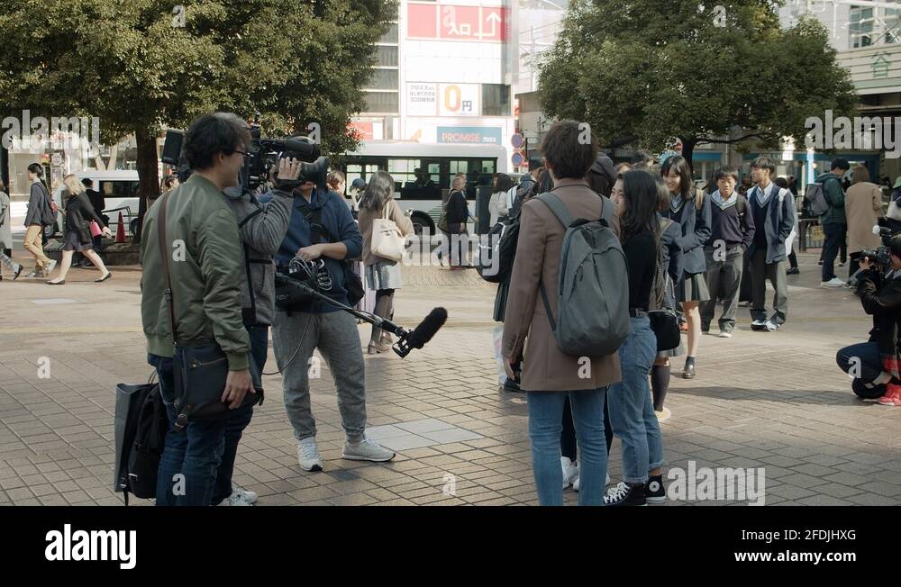 A Japanese television crew interviews two young Japanese women in front ...
