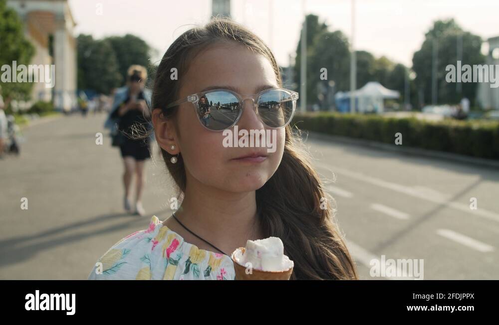 Relaxed girl walking in amusement park. Teen girl eating ice cream cone ...
