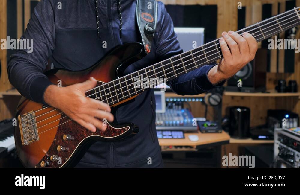 A bass player playing his electric bass guitar with the slap technique ...