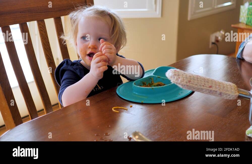 Adorable toddler girl eating spaghetti with the sauce all over her face ...