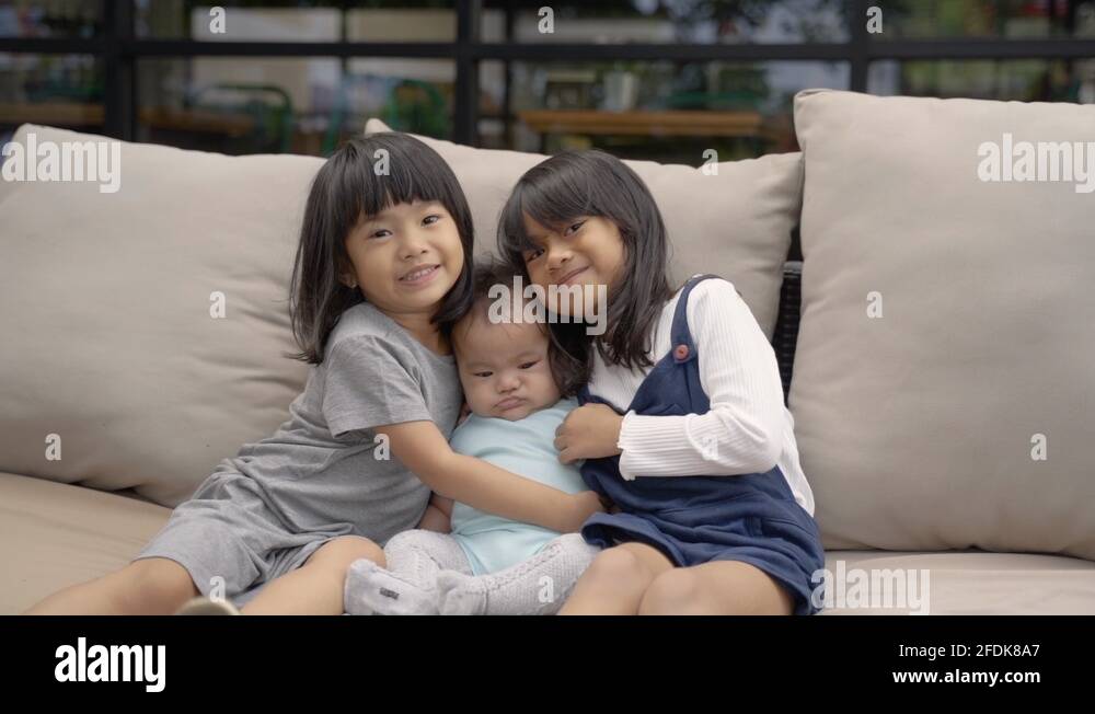 three children sitting on the couch laughing and hugging each other ...