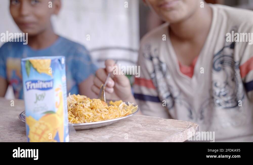Poor but happy child eating food (biryani) at a small hotel (dhaba) in ...