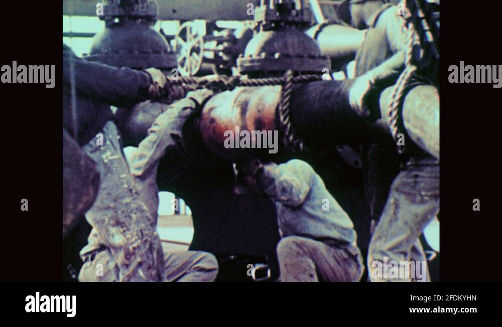 1950s: Men connecting hose to pipe. Man on ship opens valve. Hands ...