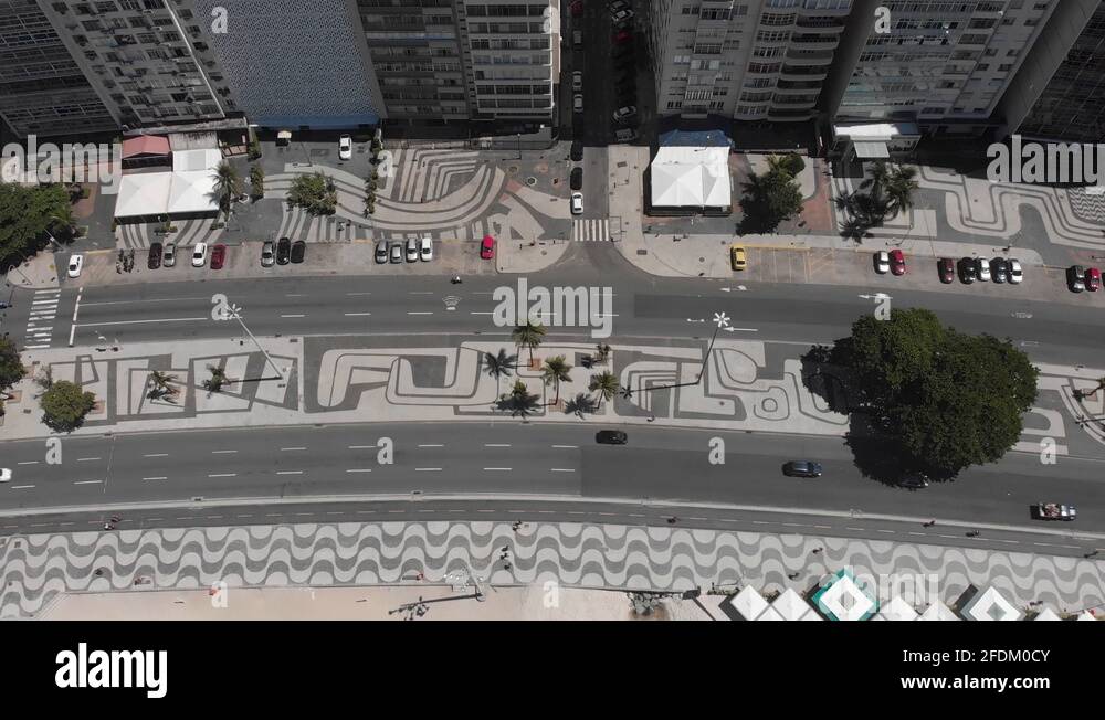 Top down pan showing Copacabana beach and boulevard road and pavement ...
