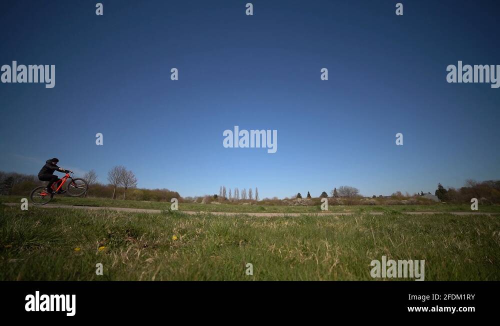 MTB Bike rider goes fast from left to right / Blue Sky & Sunshine Stock ...