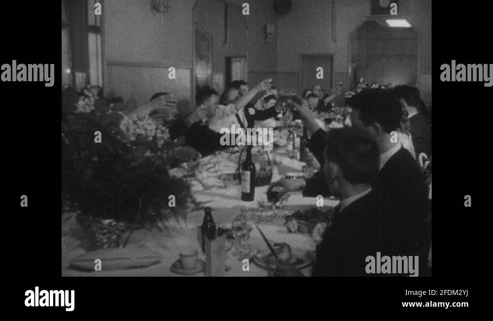 1960s: People raise glasses at wedding reception. People eat in busy ...