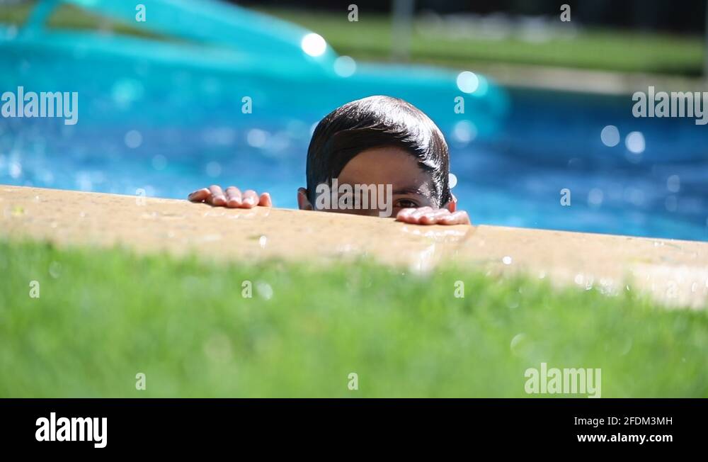 Kid holding into poolside looking to camera. Boy peeking out of ...