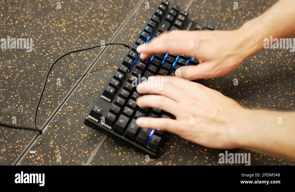 Types on the keyboard. side view. hands are typing on a multi-colored ...