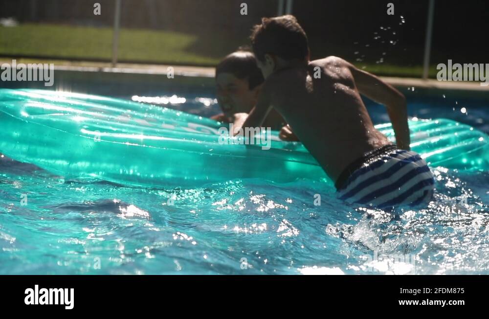 Two young brothers quarrelling at the swimming pool during summer time ...