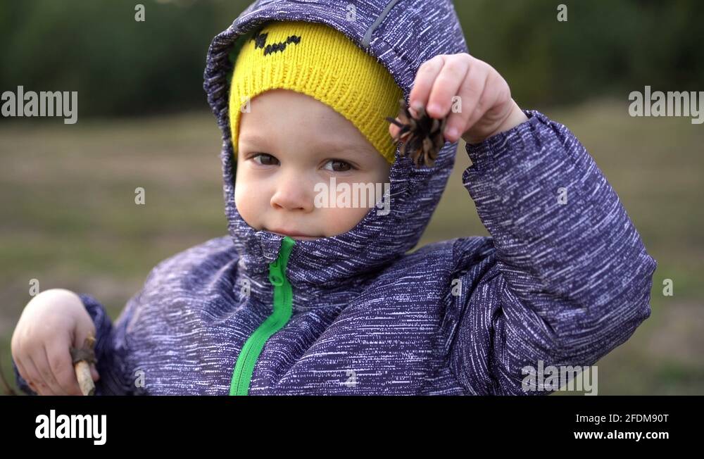 A child / boy dressed in an autumn jacket and hood holds a lump in his ...