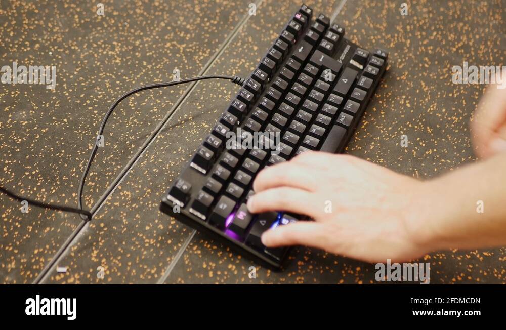 Types on the keyboard. side view. hands are typing on a multi-colored ...