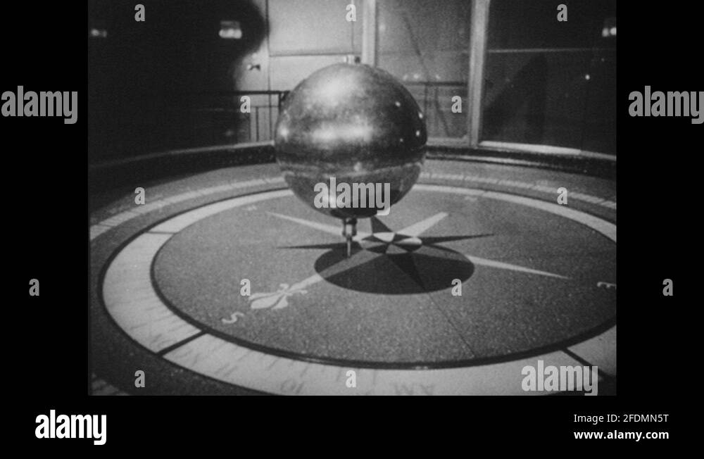 1950s: Pendulum swings. Man uses feather quill to write on scroll of ...