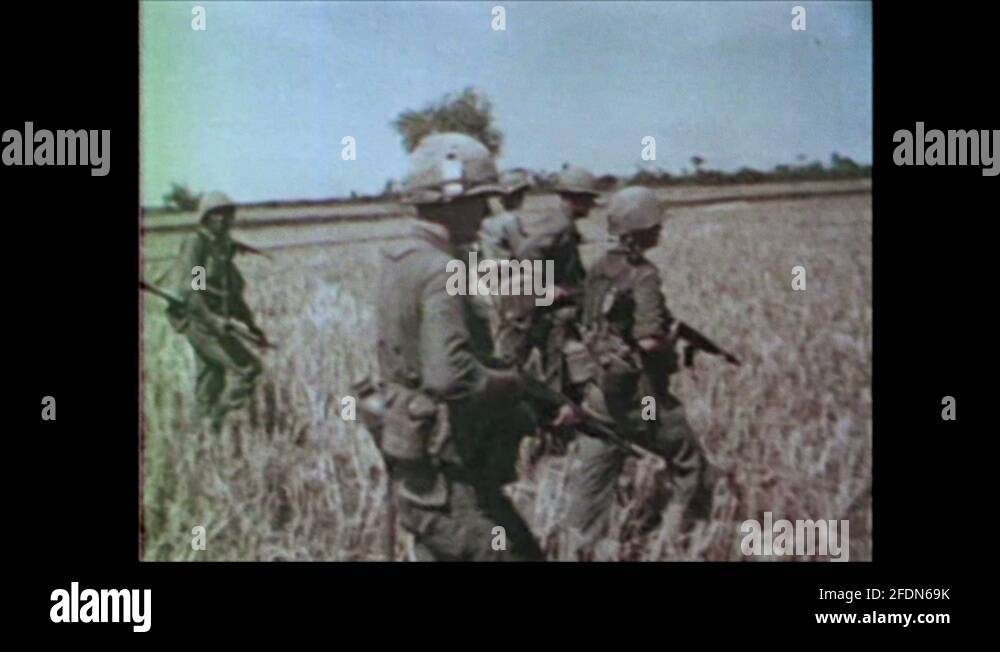 1970s: soldiers in uniform with rifles walk through field behind tank ...