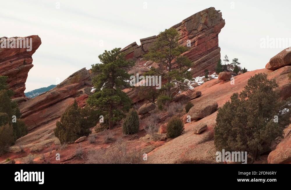 Zoom out: geological formations of red rocks and erosion on a cliffside ...