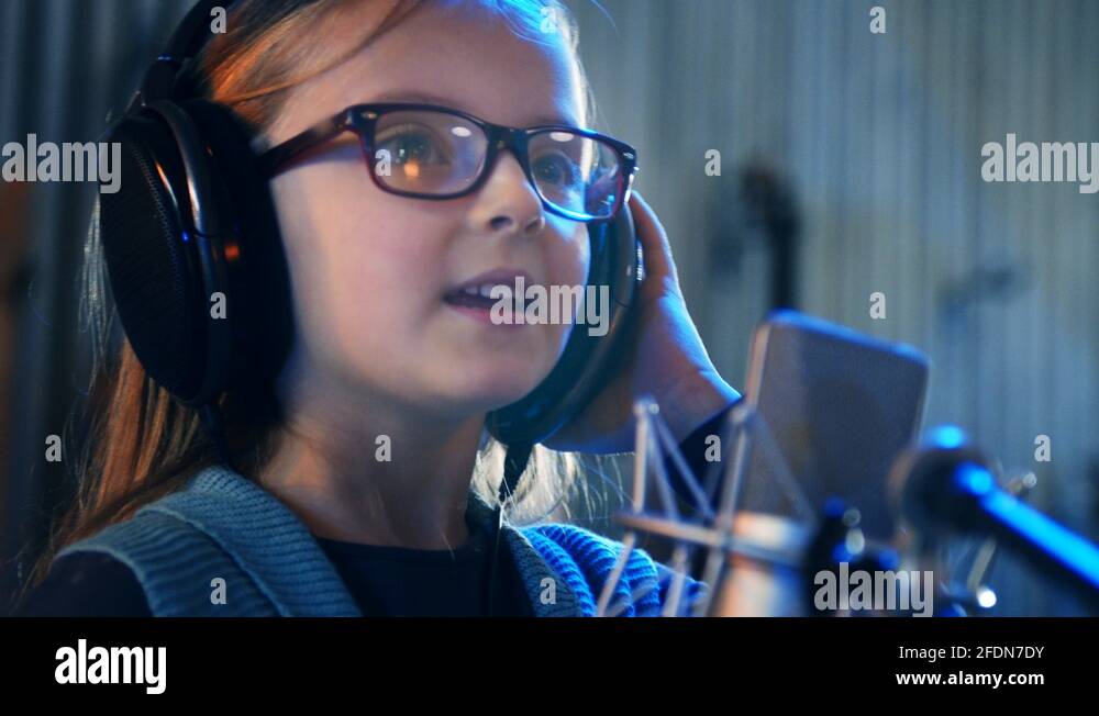 Kid singing in studio.Little girl singing a song.Front view close up ...