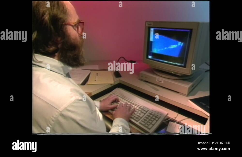 1990s: Man sits in front of computer, typing on keyboard. Light images ...
