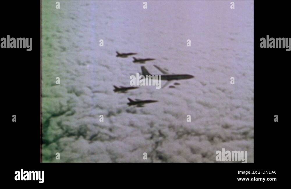 1970s: fighter jets & larger jet fly above clouds, man draws on wall ...