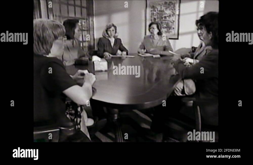 1990s: women sitting around office table pass around paper, sad woman ...