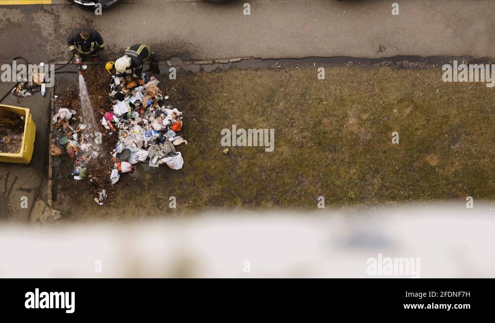 Firefighter waters dump after domestic trash bin inflamination Stock ...