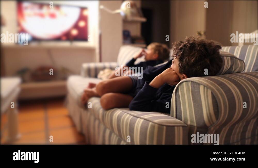 Kids in front of TV screen watching movie. Children lying on sofa couch ...