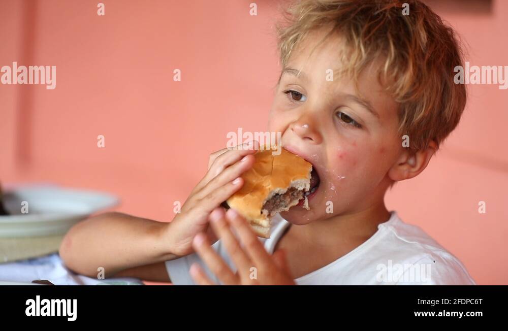 Handsome young boy eating hamburger. Child takes a bite of burger Stock ...