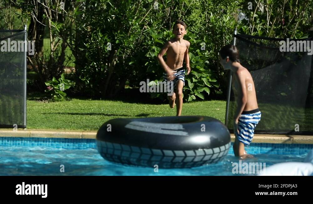 Kids have fun at the pool. Young boy running and jumping into pool ...