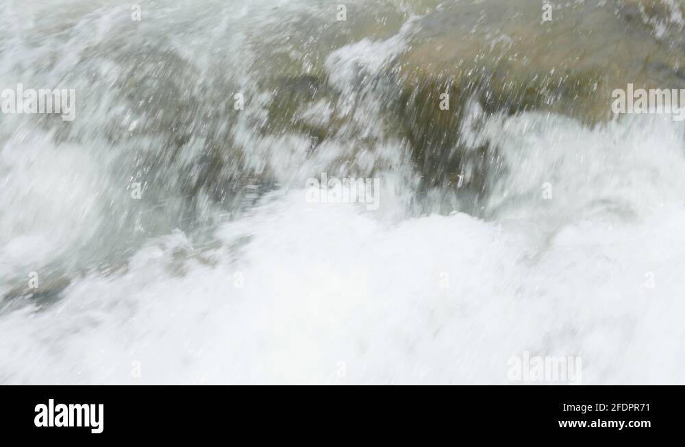A Powerful Stream forming a waterfall gushes fast with white water over ...