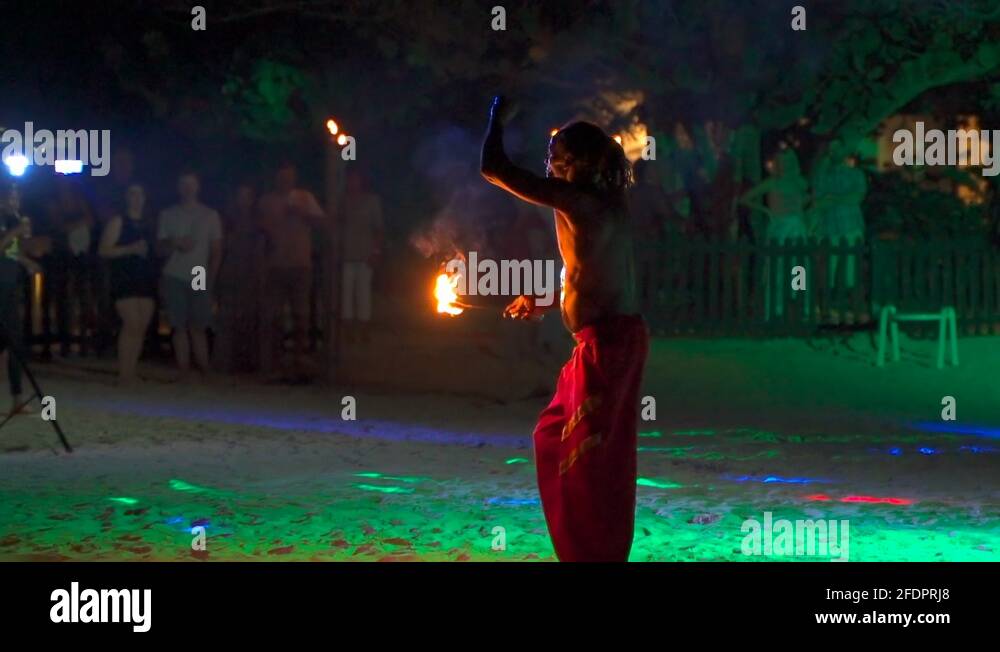 Shirtless fire-eater performing during carnival at beach, spectators ...