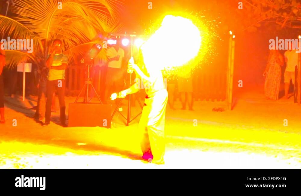 Fire-eater performing during carnival at beach, spectators watching ...