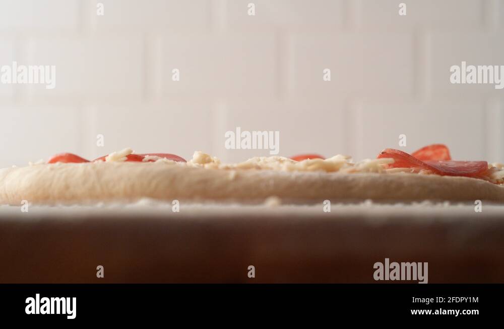 Camera follows putting a pepperoni on a pizza dough. Slow Motion Stock ...