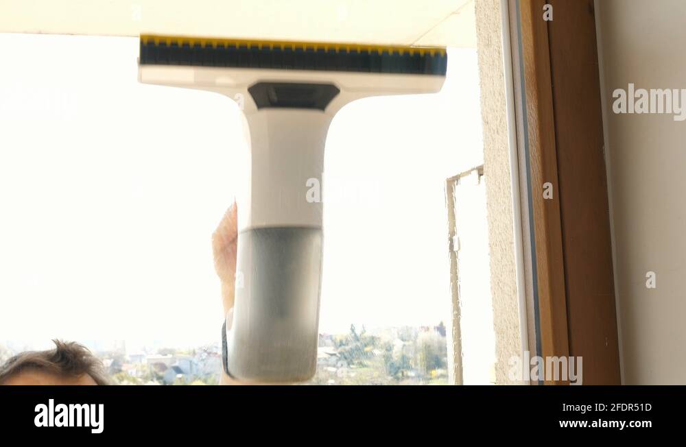 man washing the balcony window with a modern electric battery washer ...
