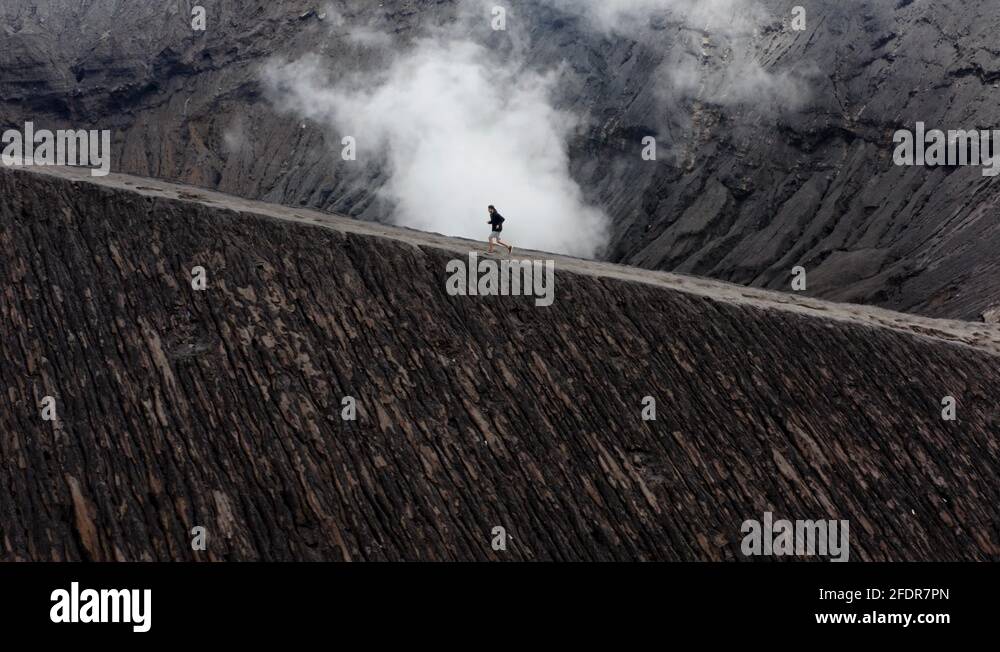 Active man running on edge of billowing Volcano in Indonesia Stock ...
