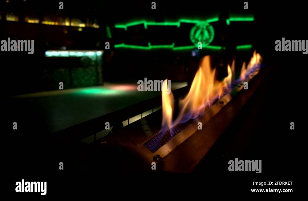 Decorative fire burns in the dark room of the night club. Empty dance ...