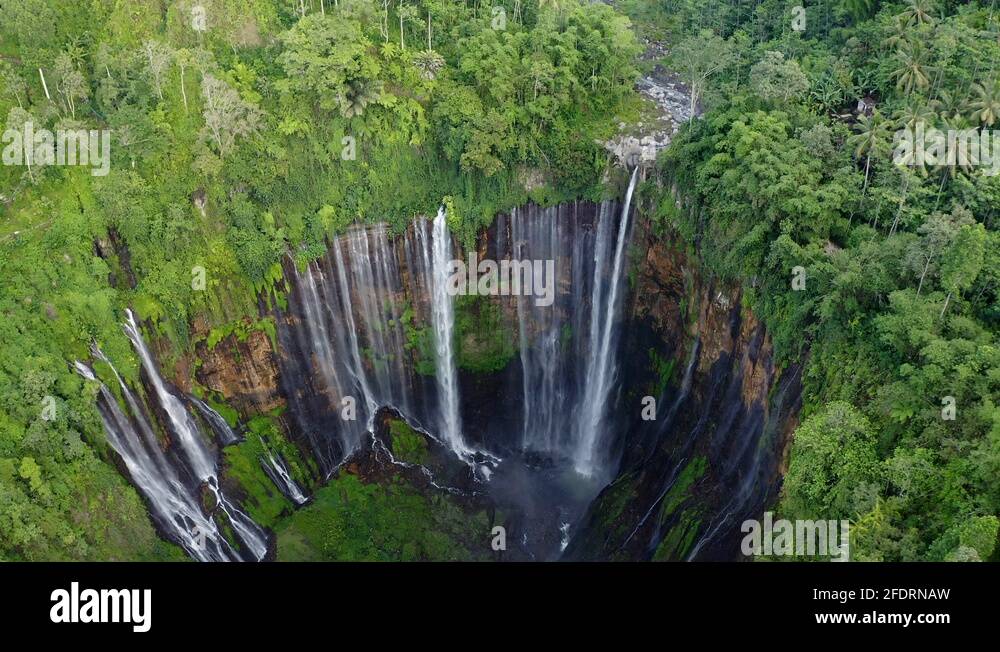 Tumpak Sewu waterfall aerial orbit shot, water flows in beautiful ...